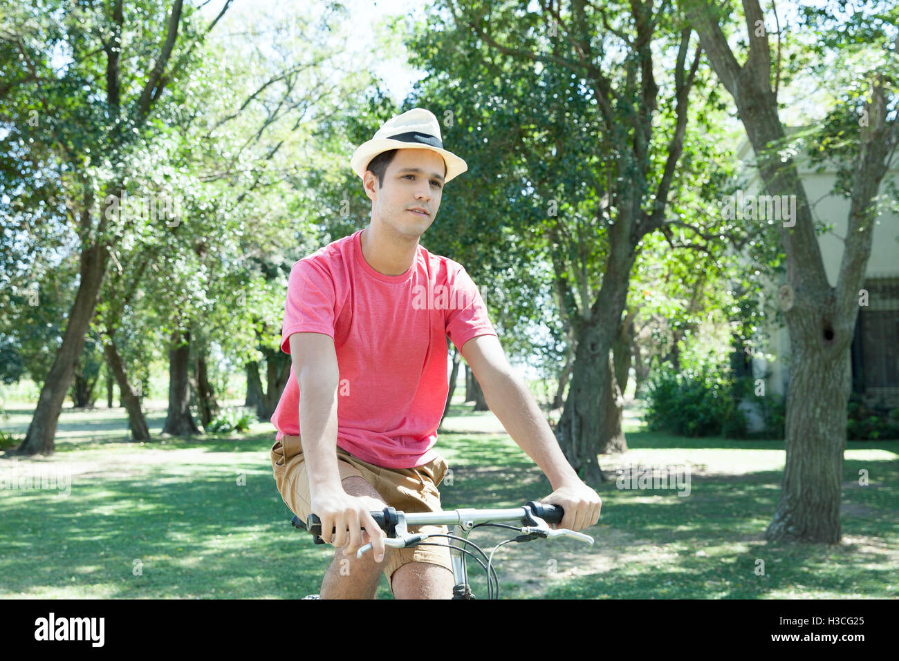 Young man riding bicycle through wooded countryside Stock Photo - Alamy