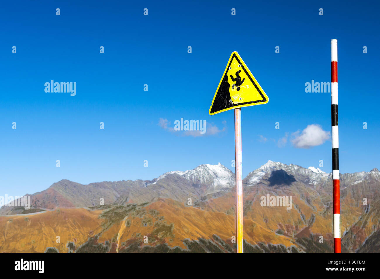 Yellow warning sign about the danger of falling down the slope. Autumn ...