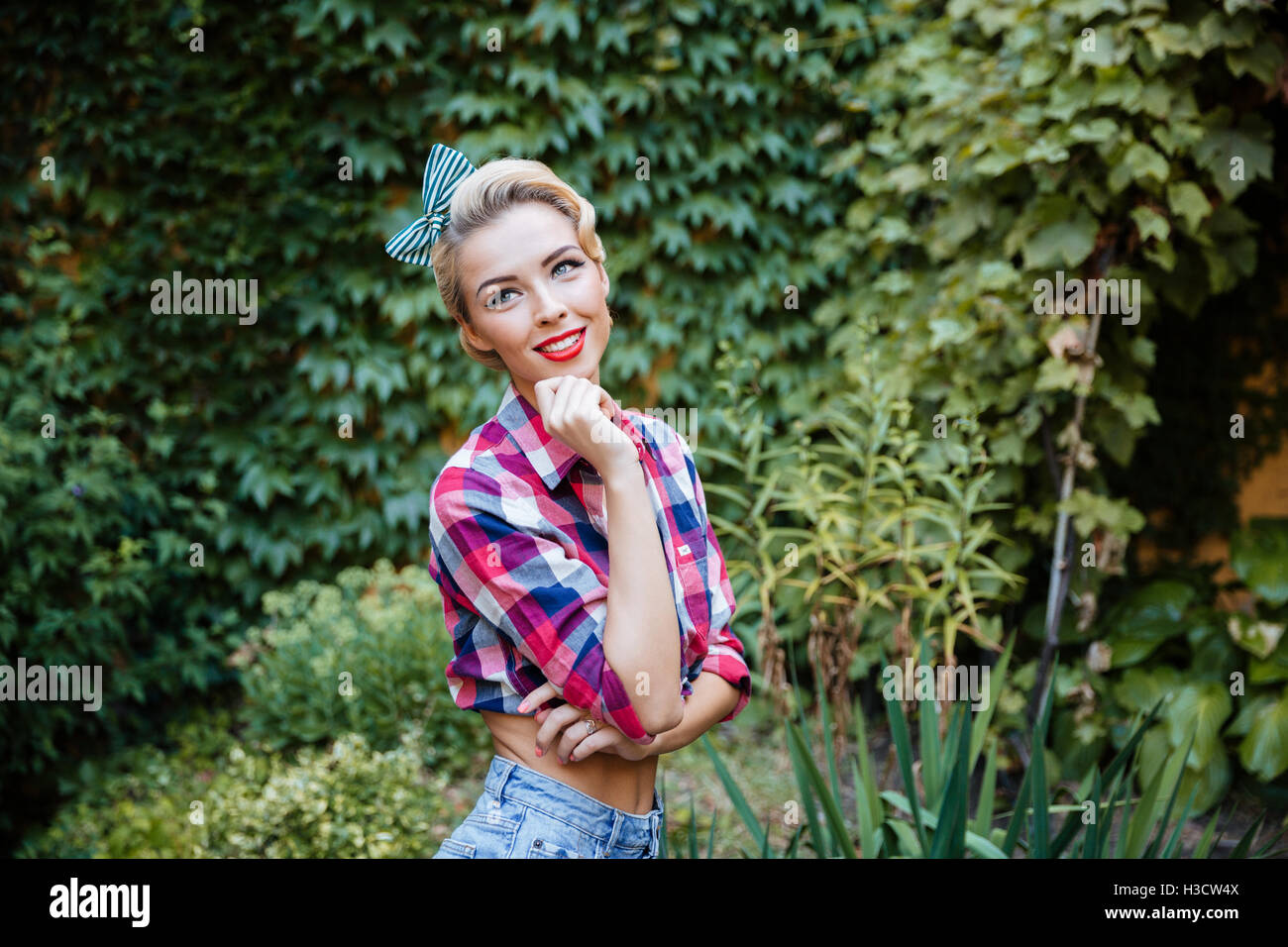Smiling pretty pin-up girl standing and dreaming in the garden Stock ...