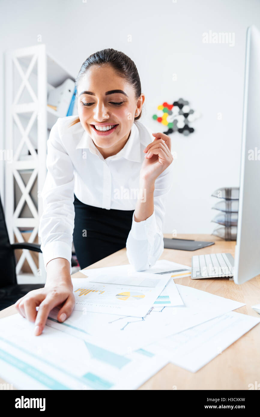 Smiling beautiful businesswoman pointing finger at graph report laying ...