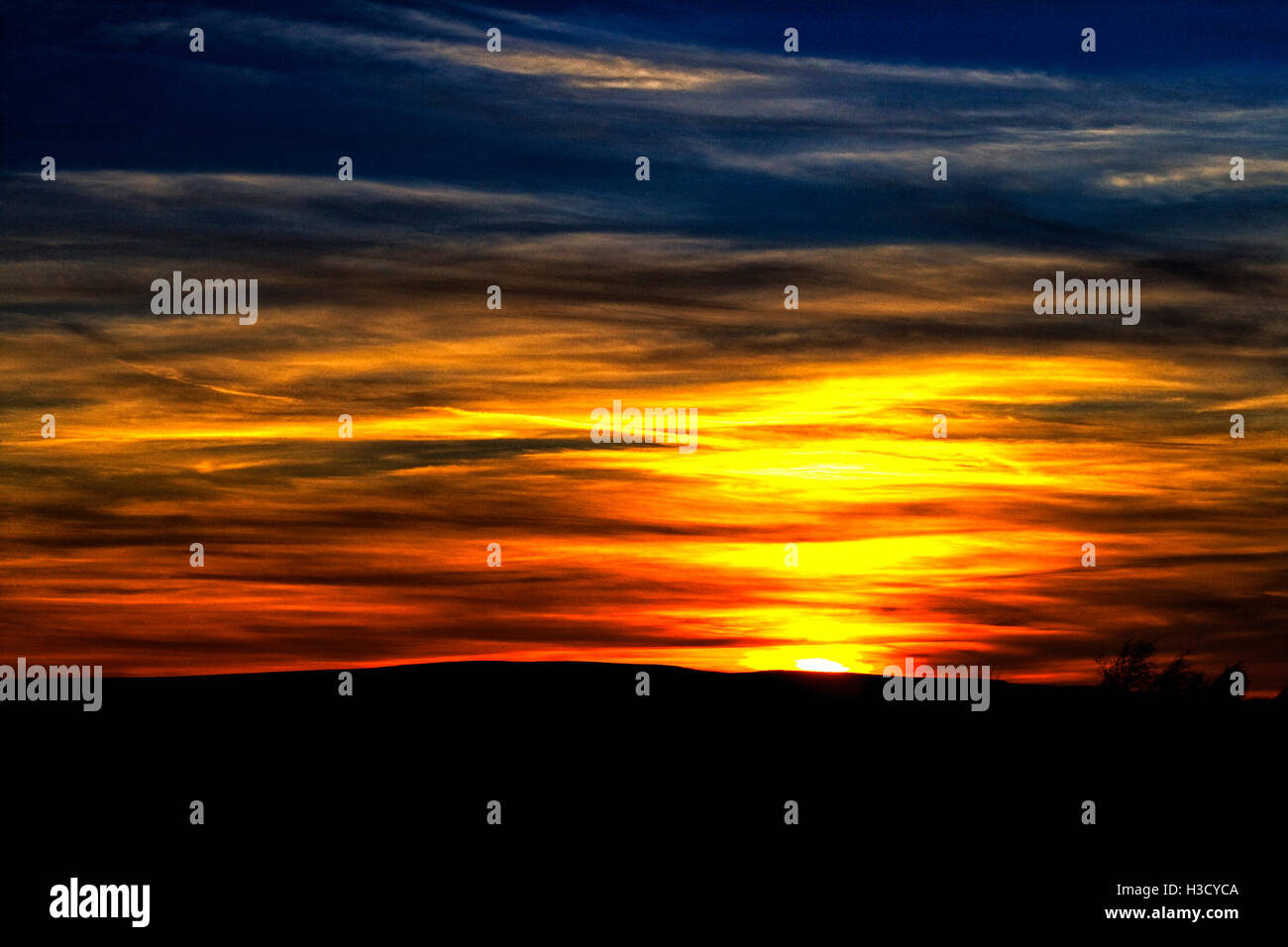 The setting sun drops below the horizon and lights up the sky in the ...