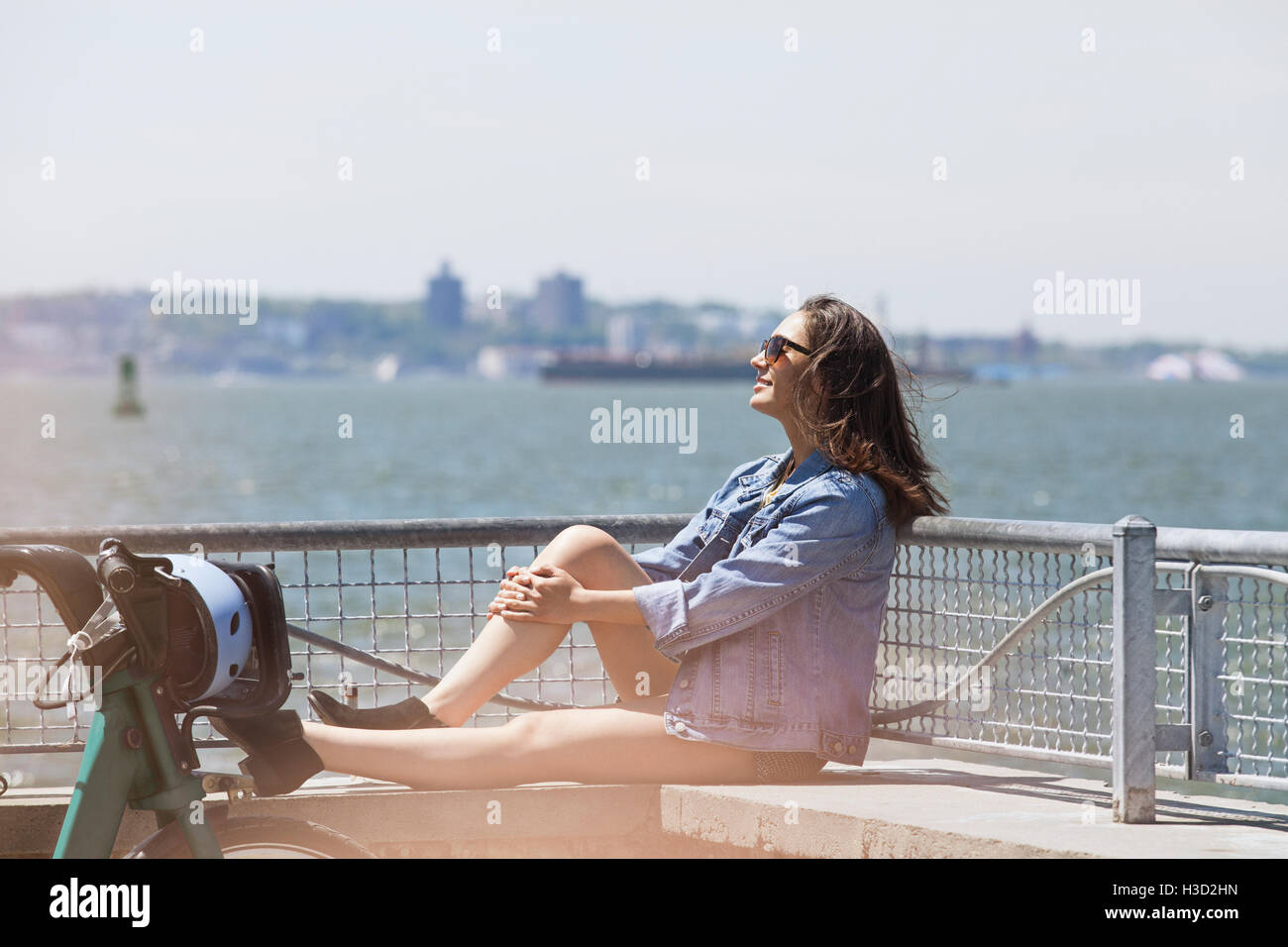 Side view of woman relaxing on retaining wall at observation point ...