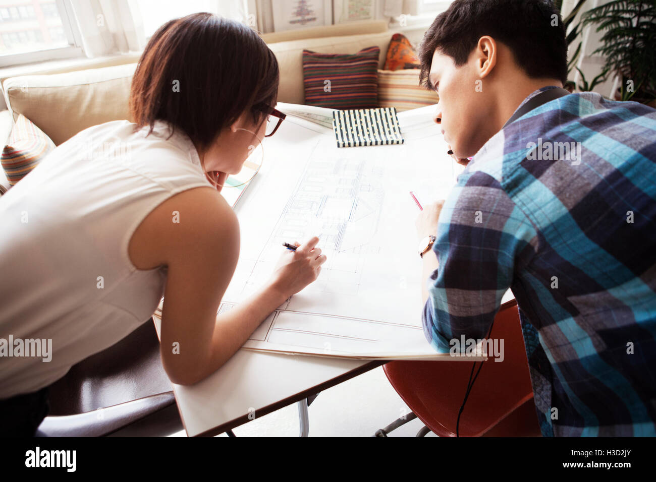 Overhead view of couple examining blueprint at home Stock Photo - Alamy