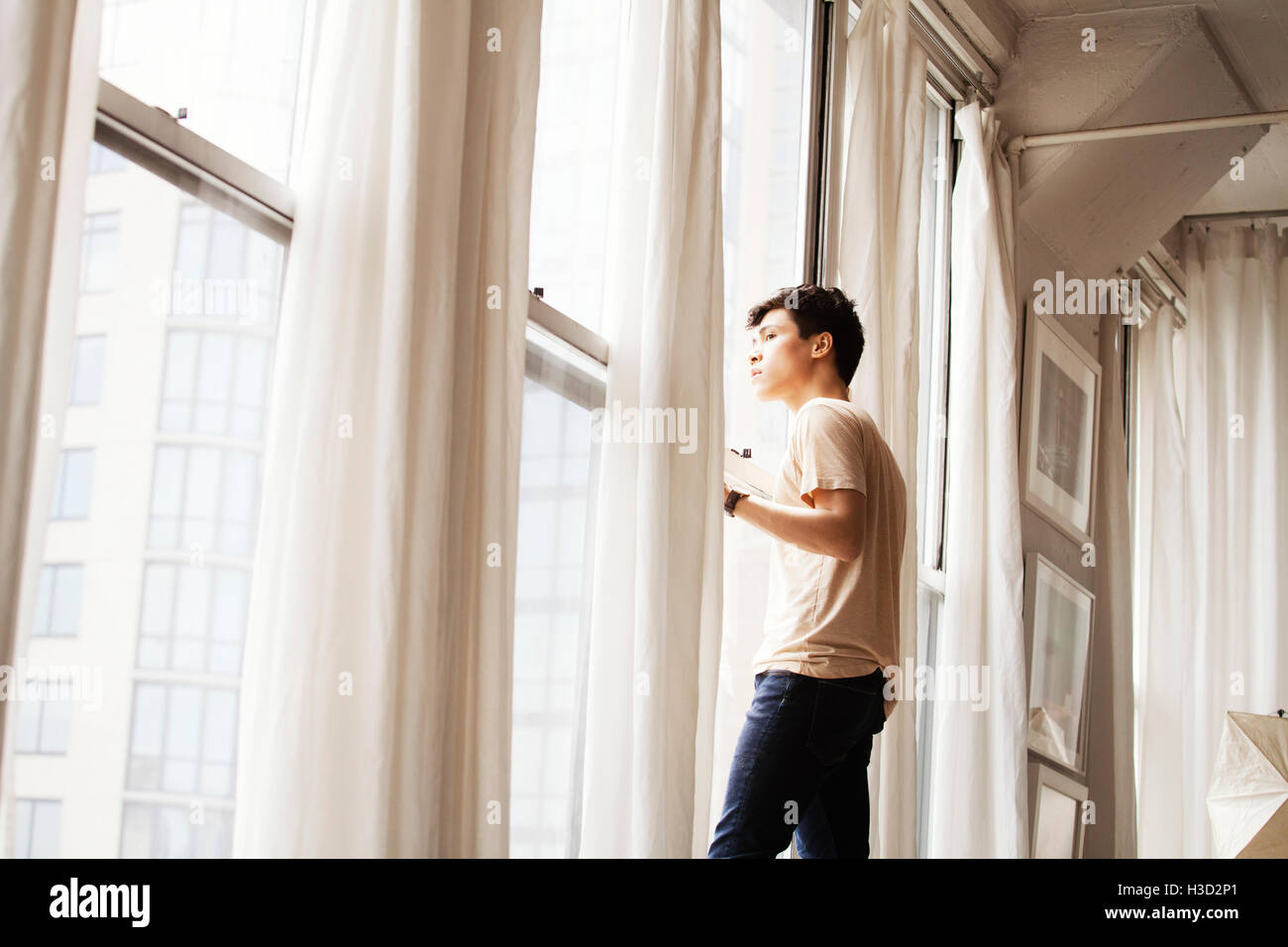Side view of thoughtful man looking through window at home Stock Photo ...