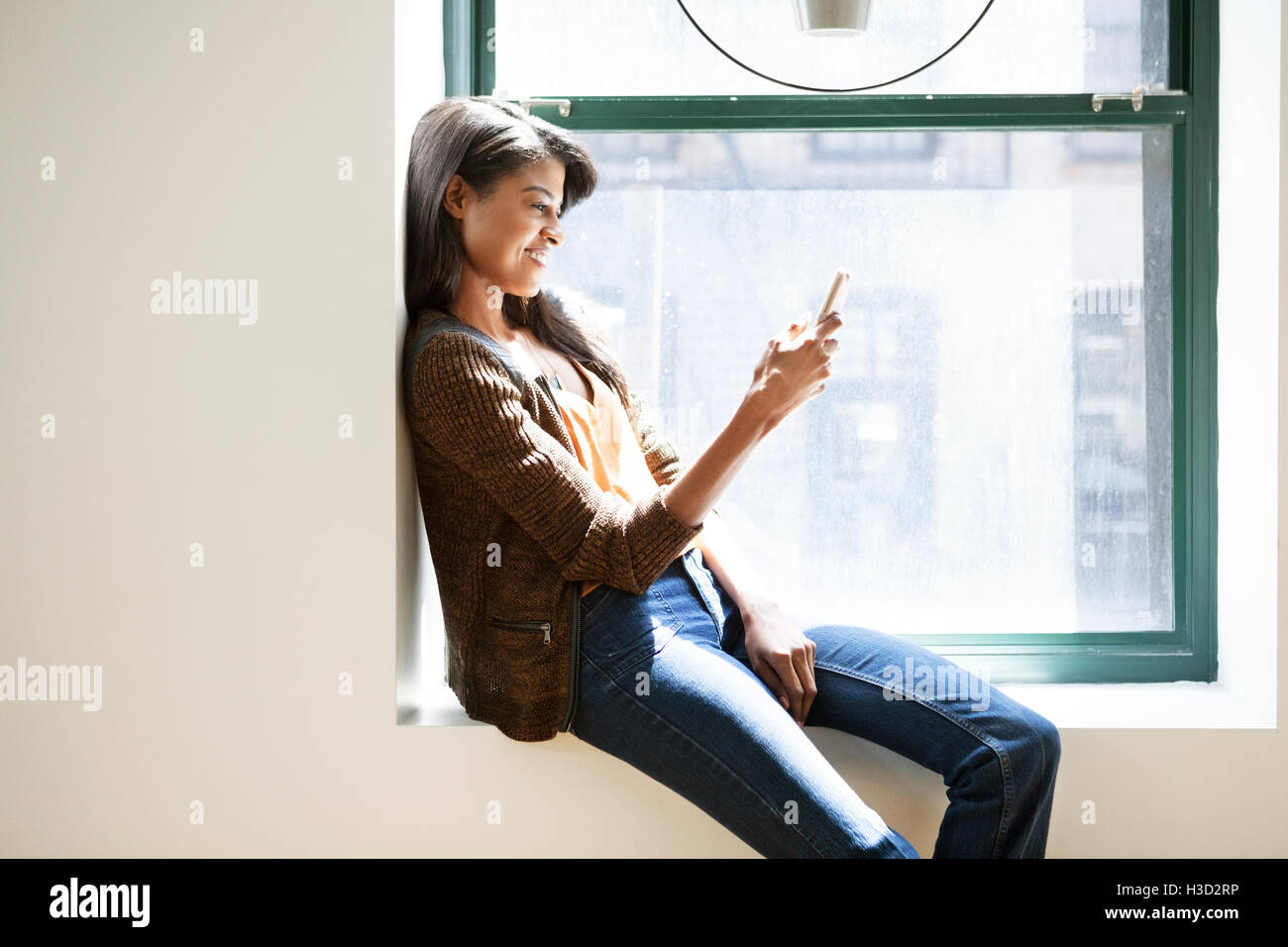 Side view of happy businesswoman using smart phone while sitting on ...
