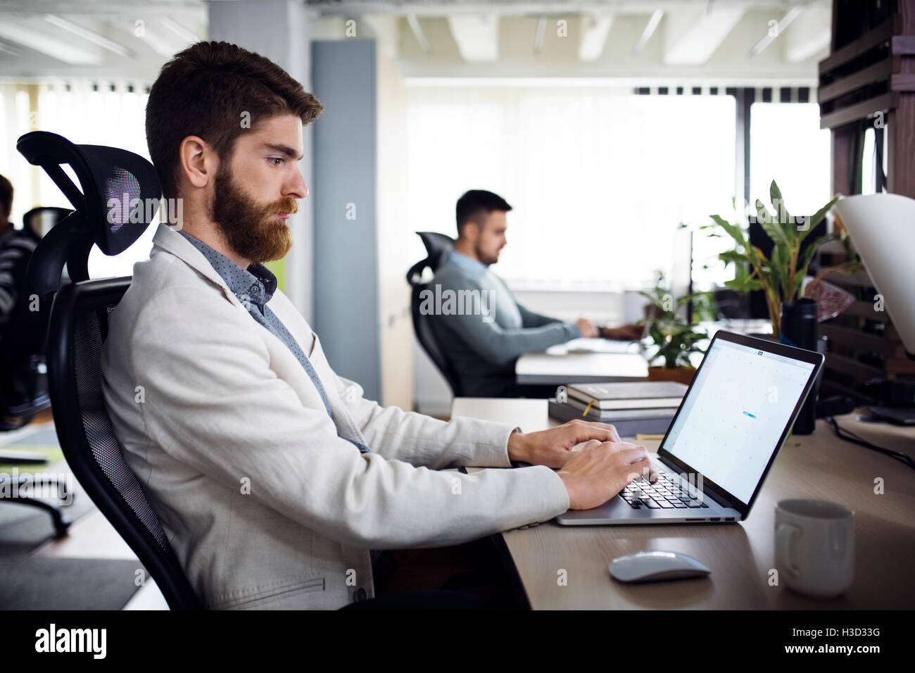 Side view of businessman using laptop in creative office Stock Photo ...