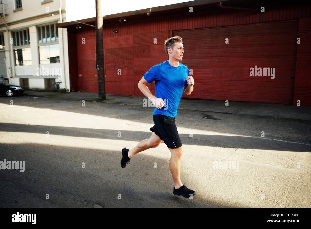 Young man jogging on street in city Stock Photo - Alamy
