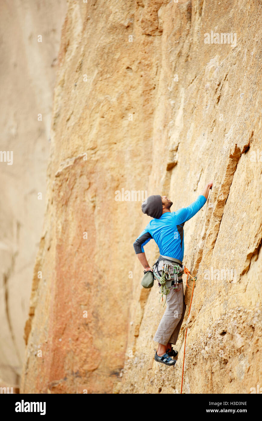 Male climber looking up while climbing mountain Stock Photo - Alamy