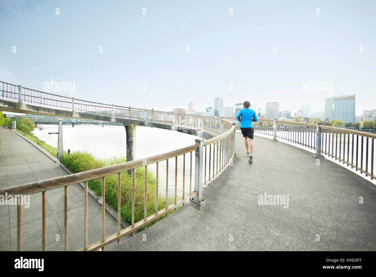 Rear view of athlete running on bridge against clear sky Stock Photo ...