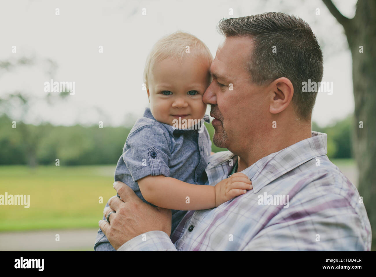Father carrying baby boy at park Stock Photo - Alamy