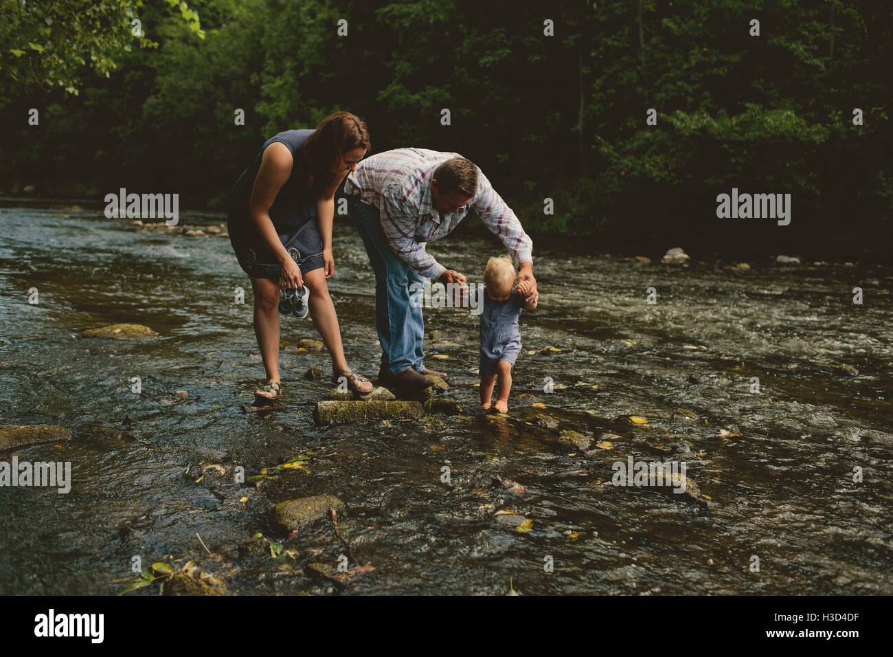 Happy family enjoying in stream Stock Photo - Alamy
