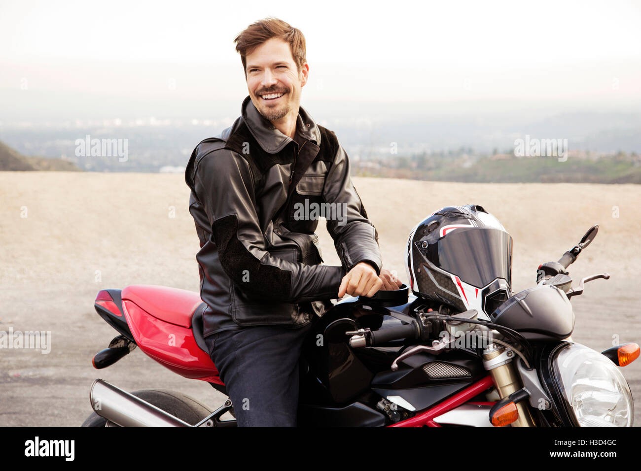 Cheerful biker sitting on motorcycle at countryside Stock Photo - Alamy