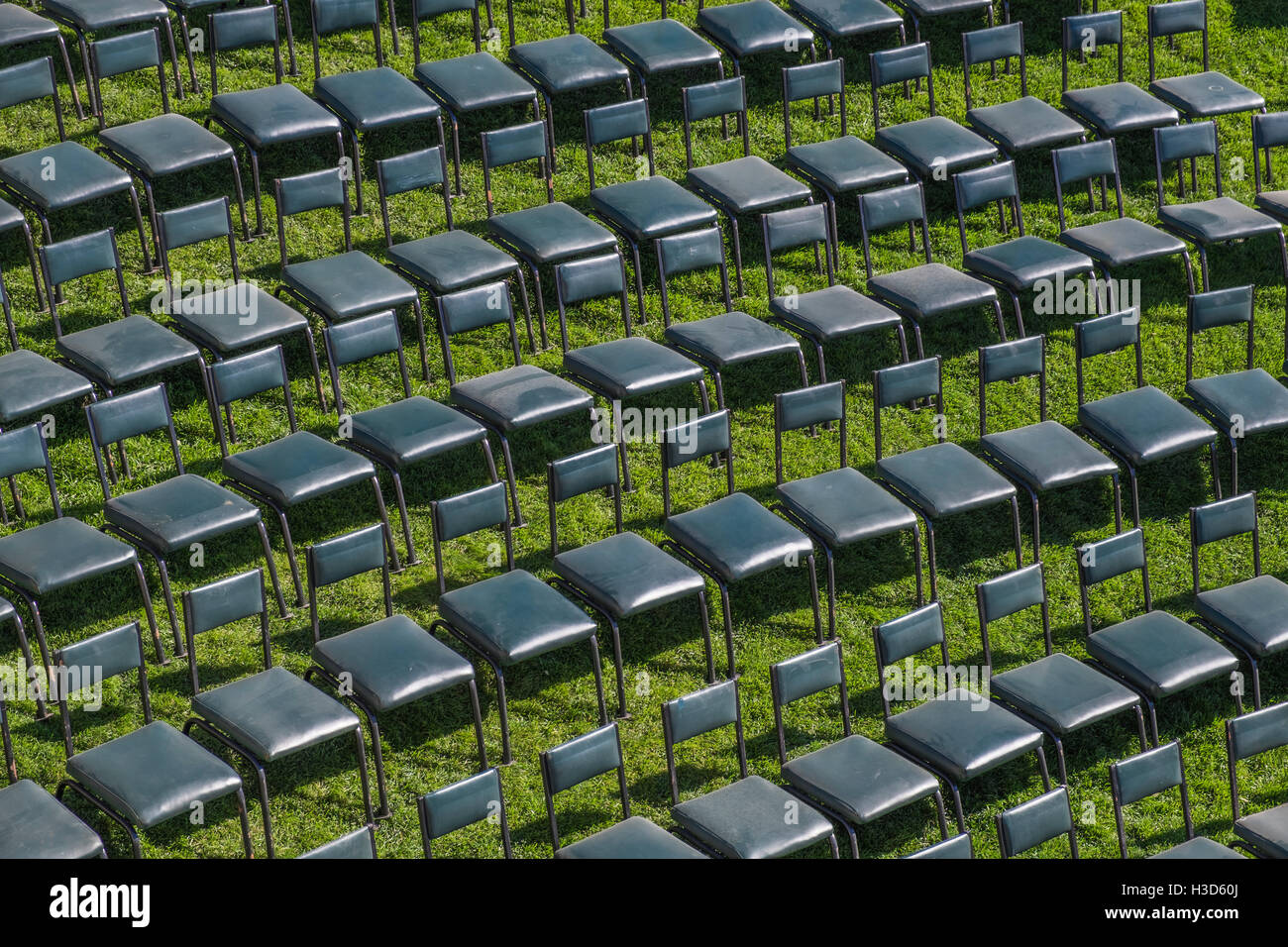 Seats placed on the grass in an outdoor venue reflect the overhead sun ...