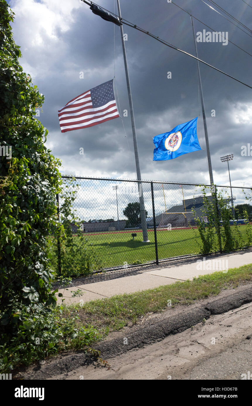 United States and Minnesota State Flags flying at half-staff against a ...