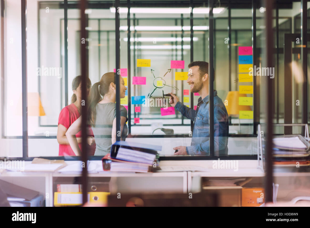 Creative teamwork in front of glass wall using post it notes and ...