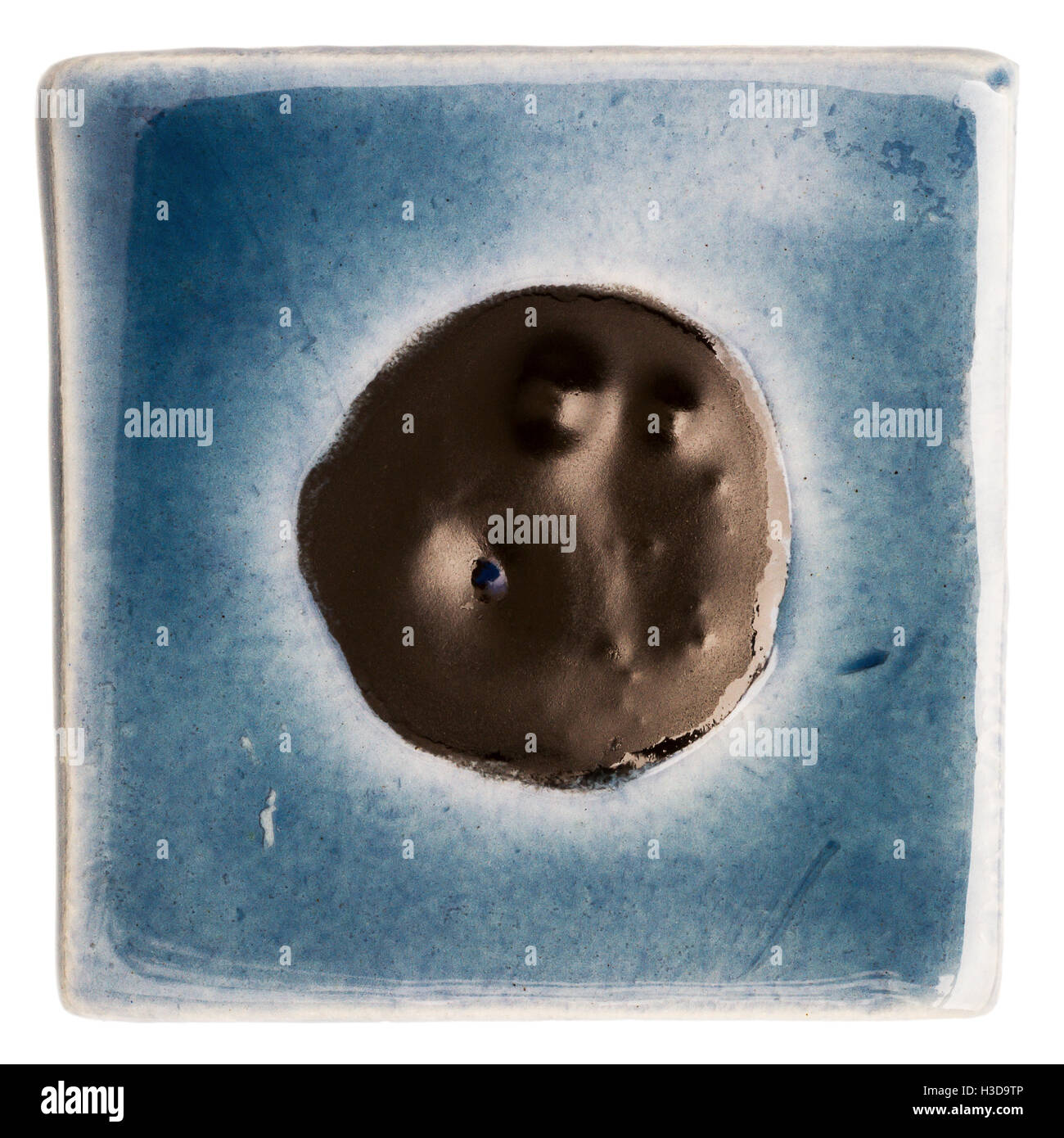 Blue handmade glazed ceramic tile with big black dot in middle isolated ...