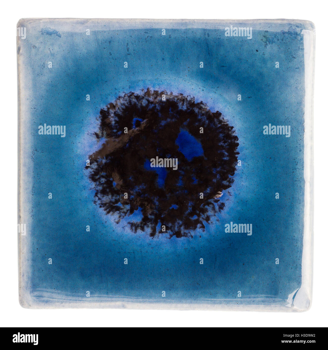Blue handmade glazed ceramic tile with big black dot in middle isolated ...