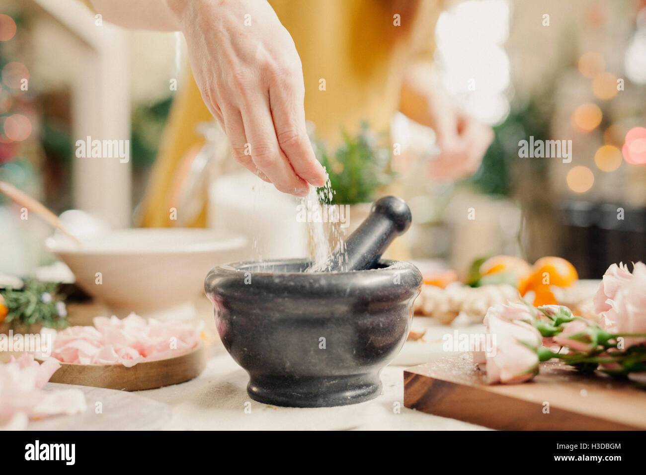 A hand adding ingredients to a pestle and mortar on a kitchen counter ...