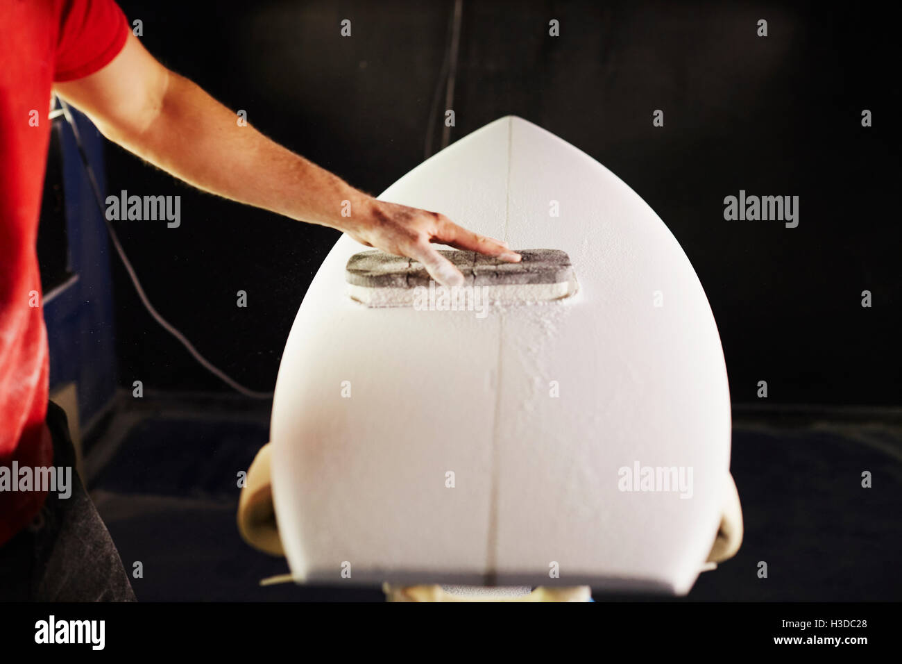 Close up of a man sanding a surfboard in a workshop Stock Photo - Alamy