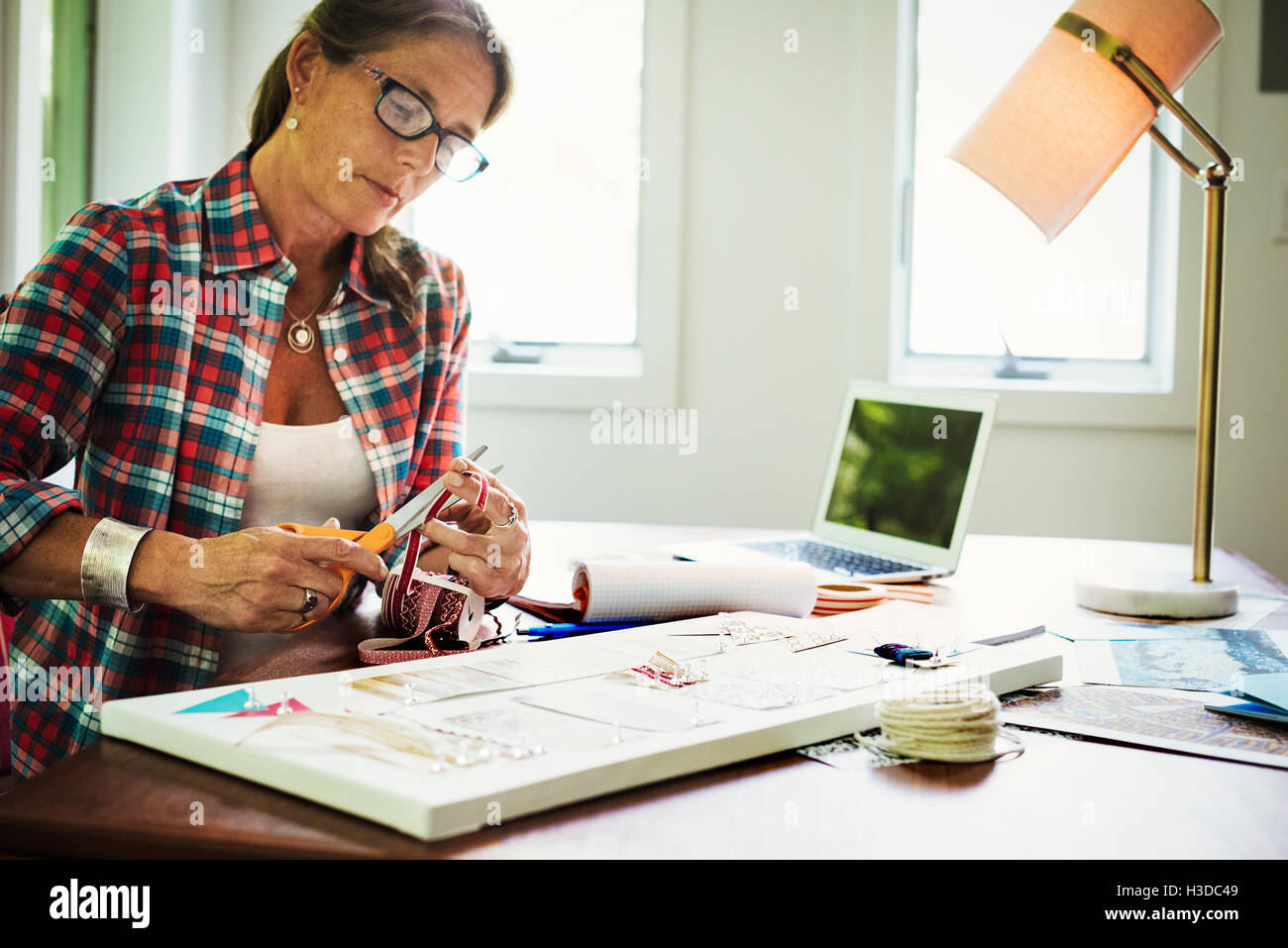 A woman creating a collage picture with material and paper Stock Photo ...