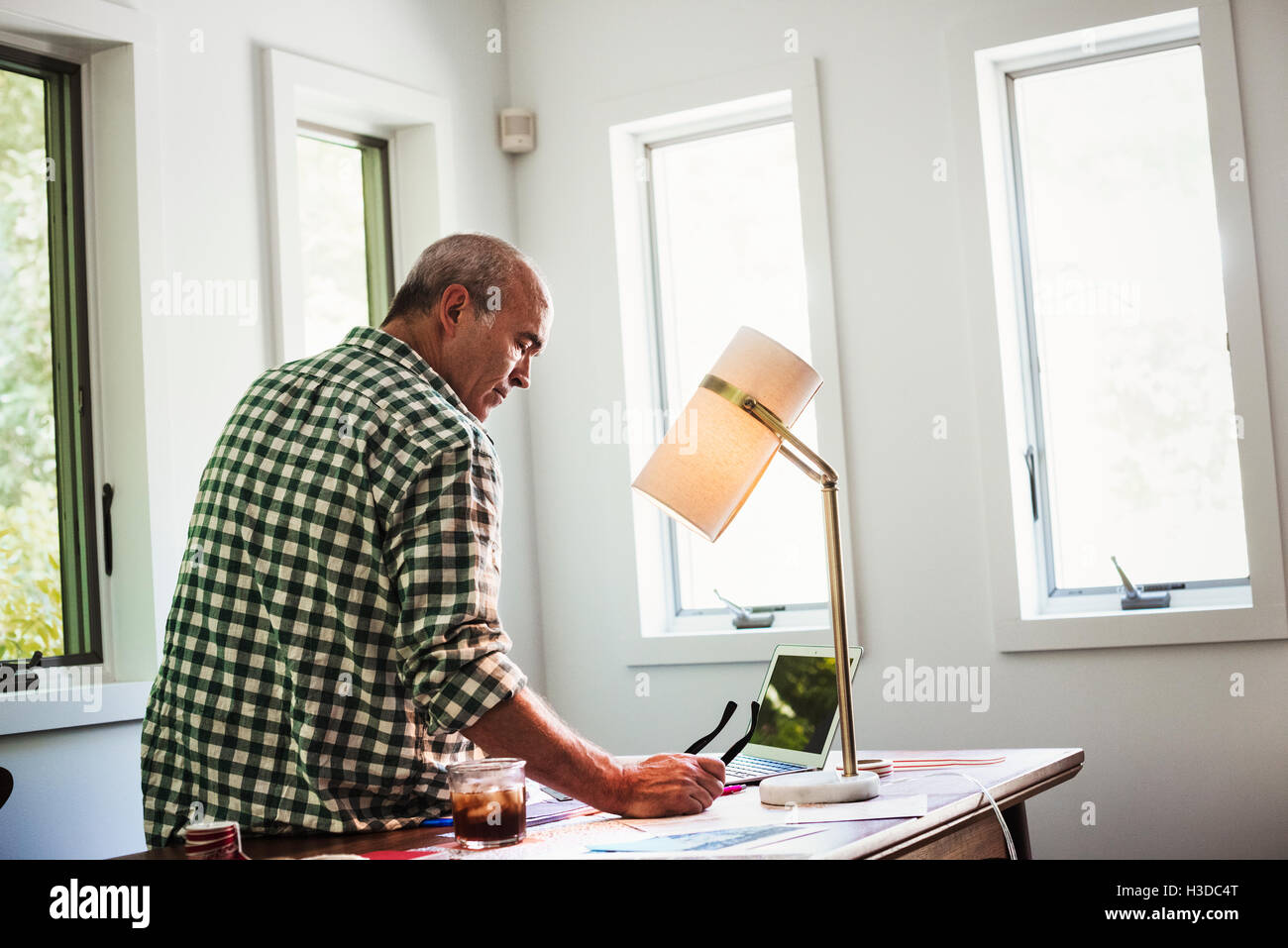 A man at home using a laptop on a desk Stock Photo - Alamy