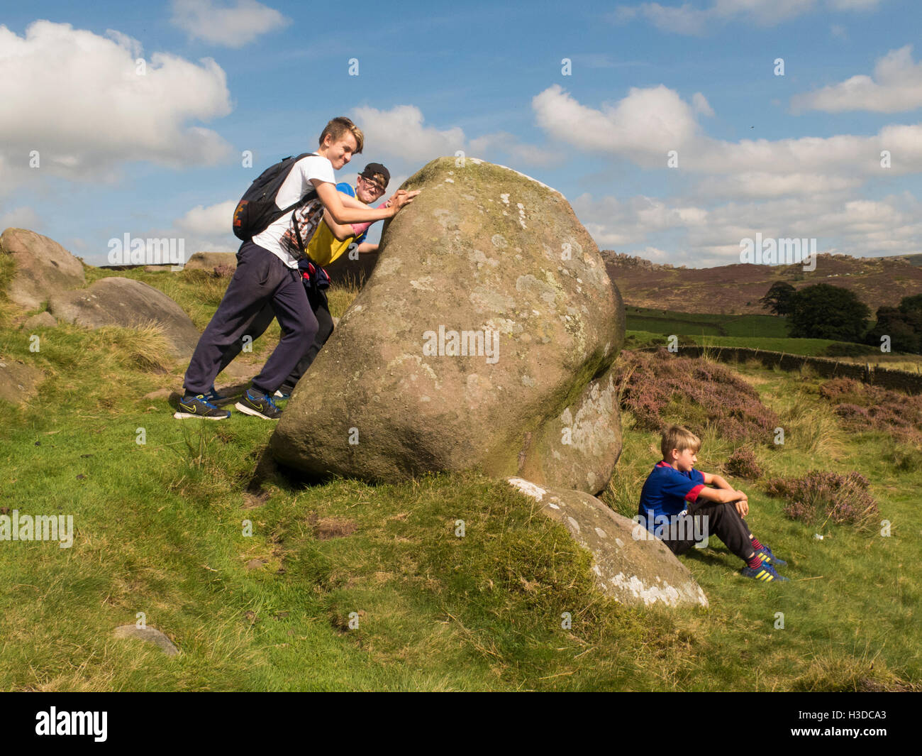 Boys pushing rock Stock Photo - Alamy