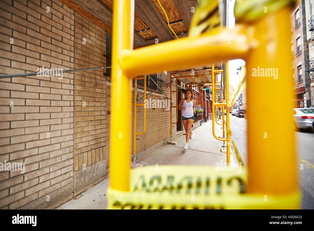 A young asian woman runs by a construction site on a city street Stock ...