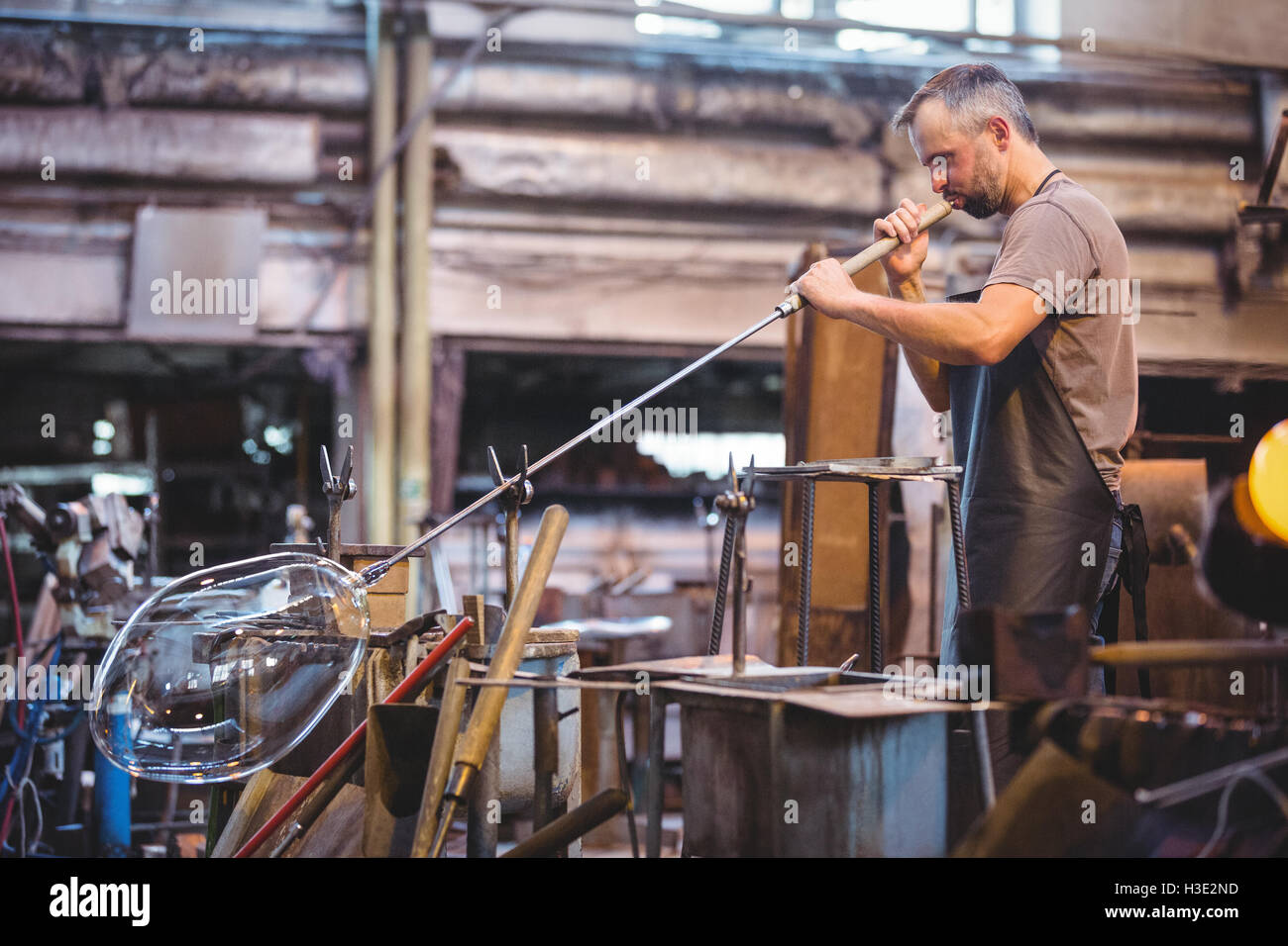 Glassblower shaping a glass on the blowpipe Stock Photo - Alamy