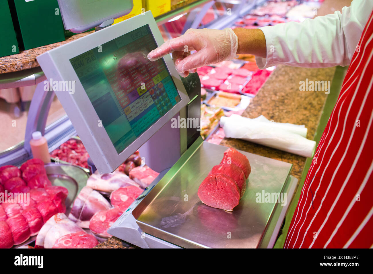 Mid section of butcher checking the weight of meat at counter Stock ...