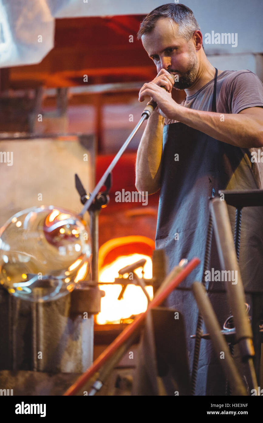 Glassblower shaping a glass on the blowpipe Stock Photo - Alamy