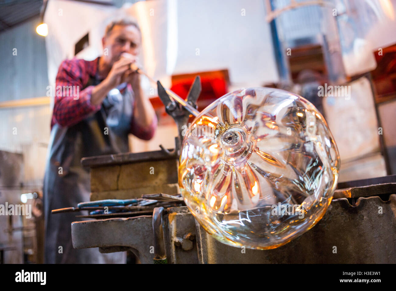 Glassblower shaping a glass on the blowpipe Stock Photo - Alamy