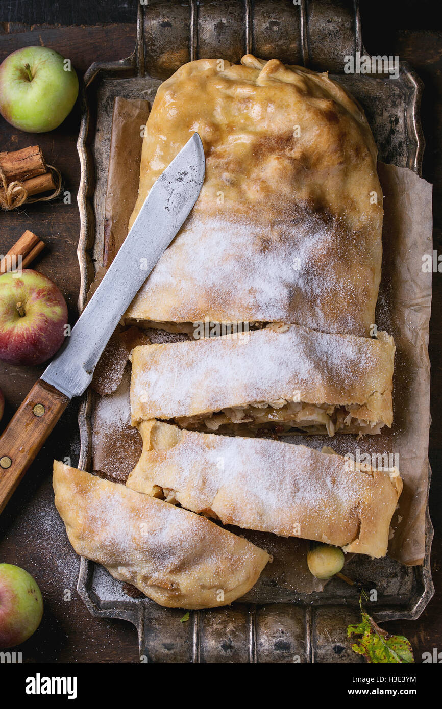 Sliced homemade apple strudel served with fresh apples with leaves ...
