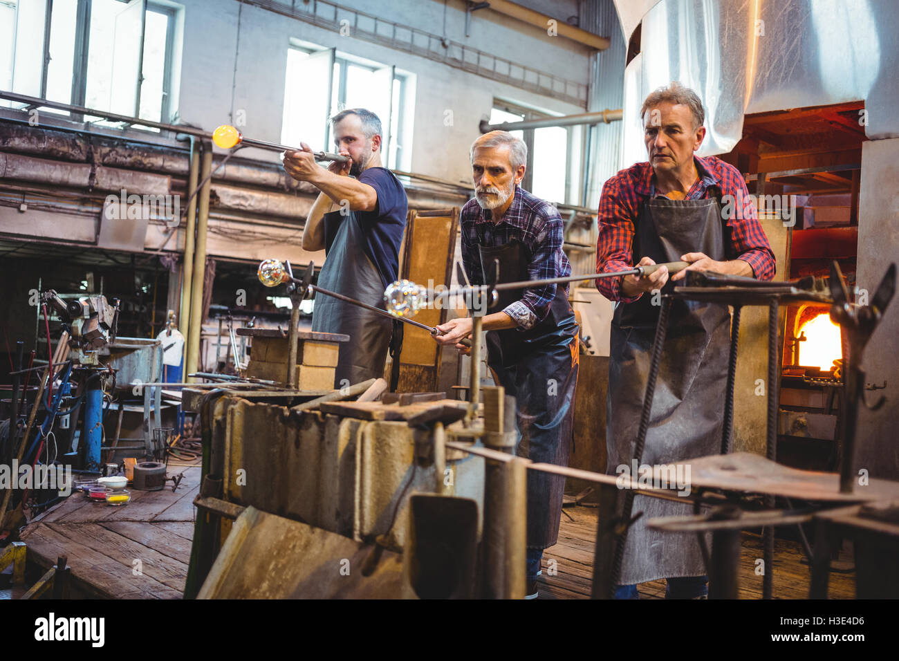 Team of glassblowers shaping a glass on the blowpipe Stock Photo - Alamy