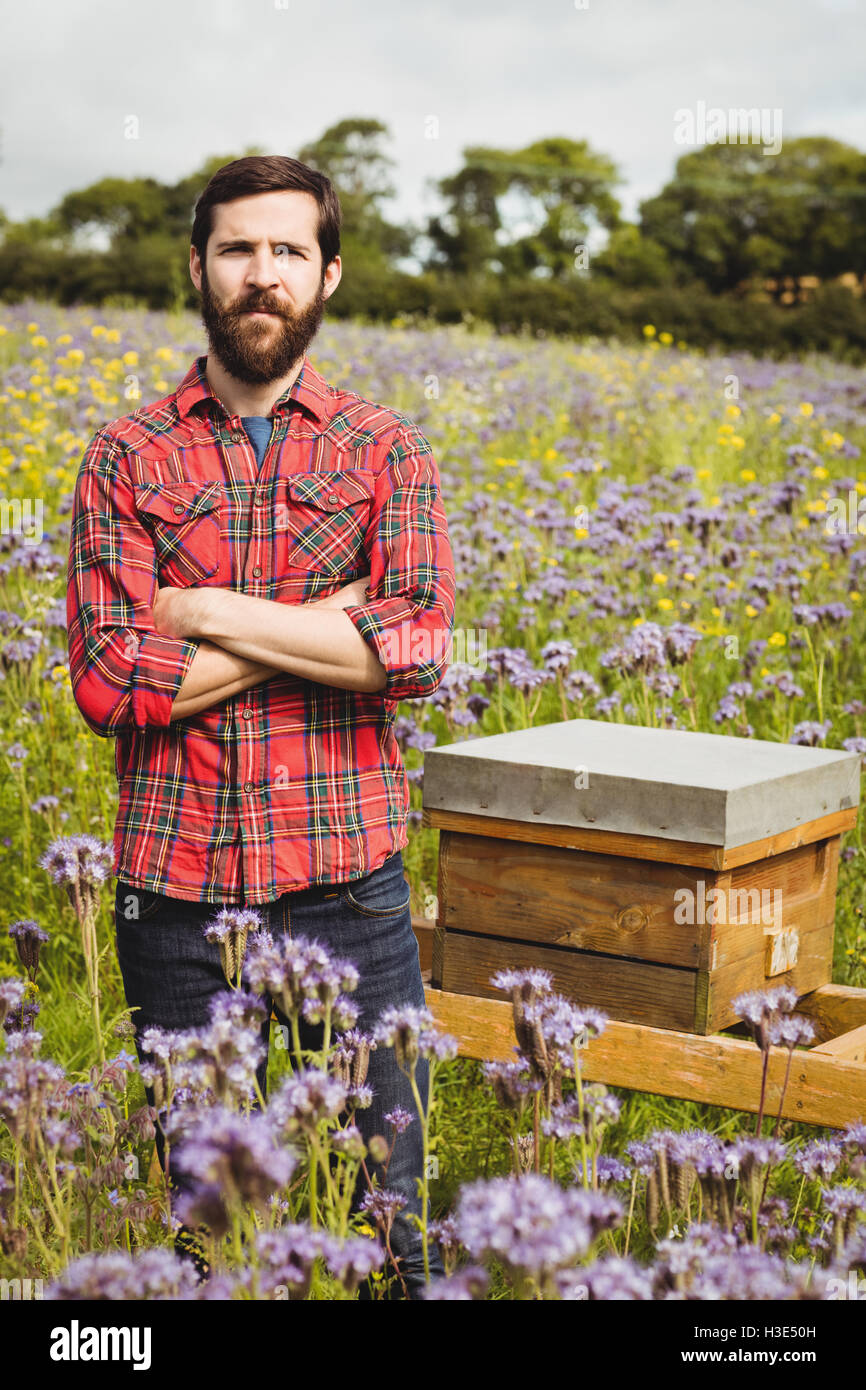 Beekeeper standing with arms crossed in flower field Stock Photo - Alamy