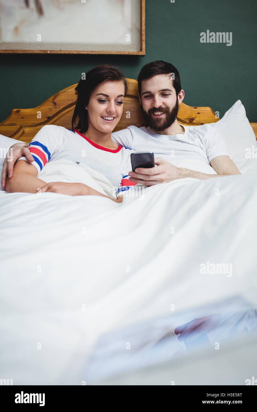 Couple using mobile phone on bed Stock Photo - Alamy