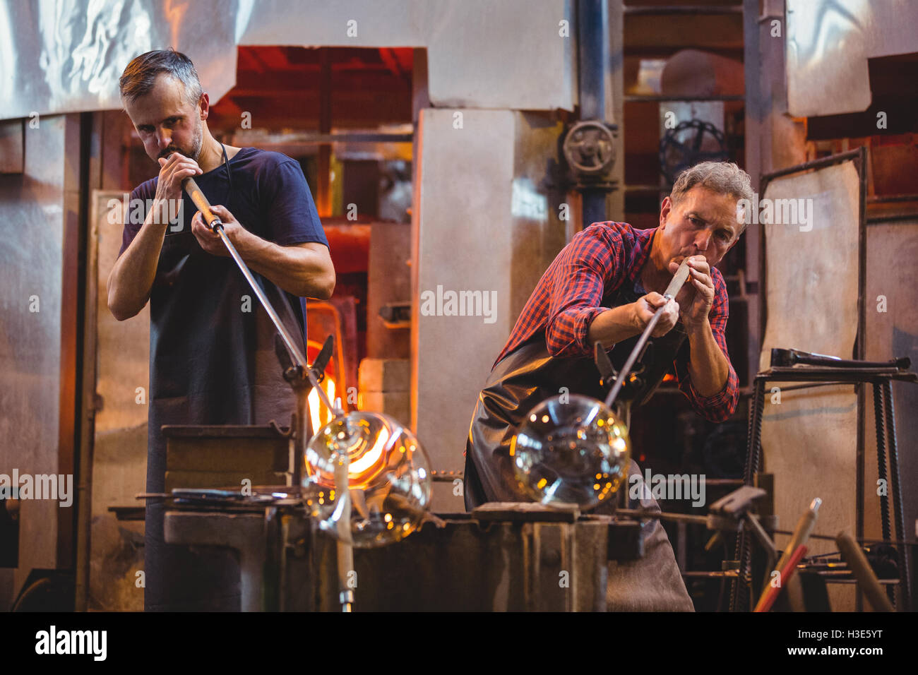 Glassblower shaping a glass on the blowpipe Stock Photo - Alamy