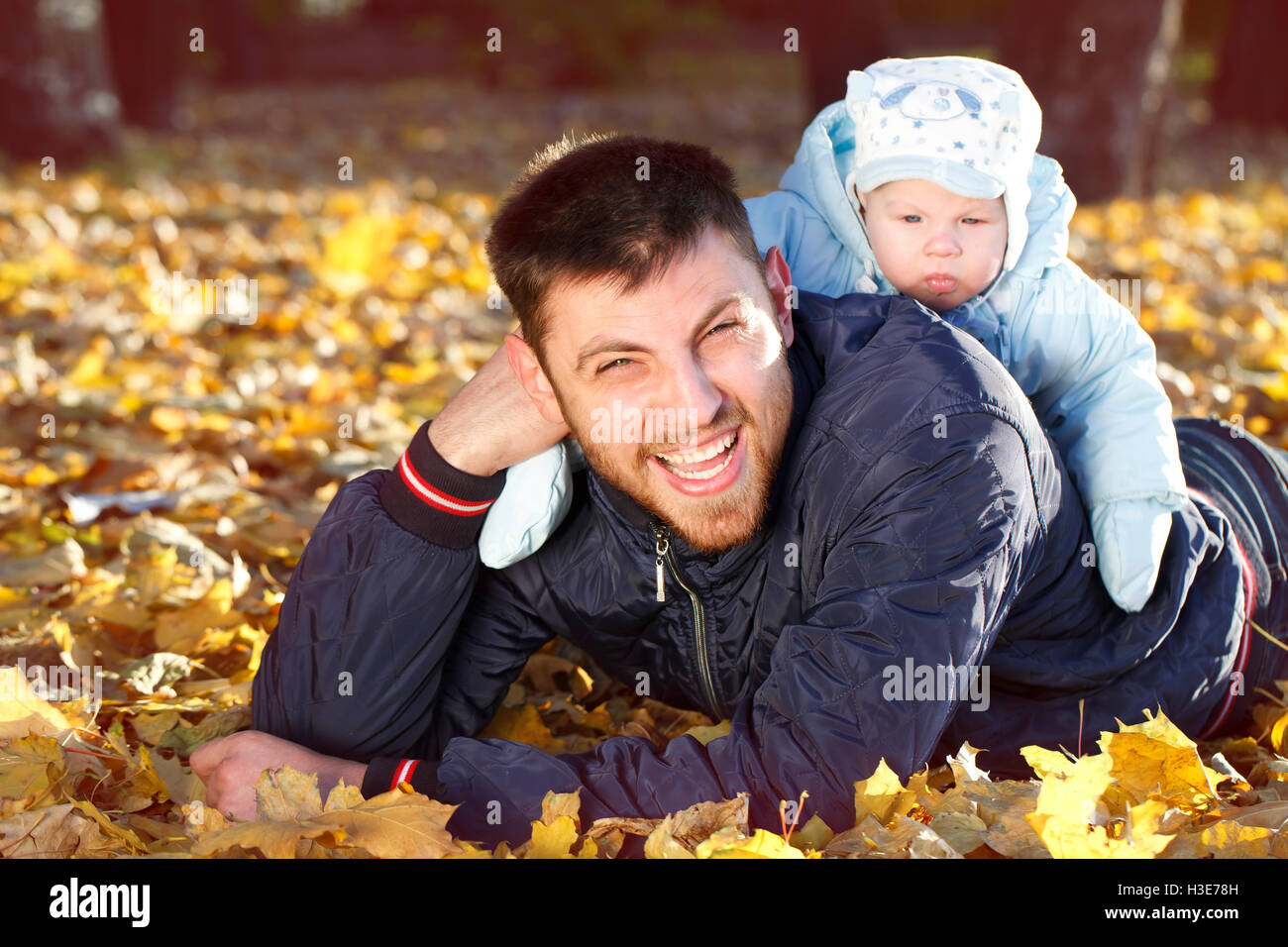 Happy smiling dad with a baby on a background of yellow leaves Stock ...
