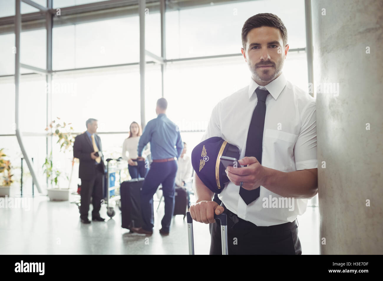 Portrait of pilot using mobile phone in waiting area Stock Photo - Alamy