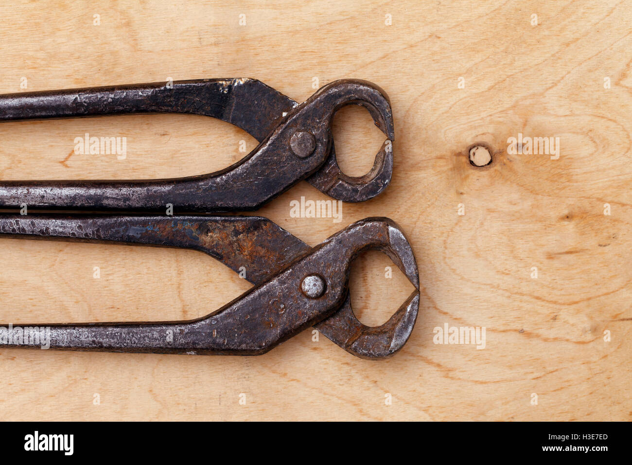 a old vintage tongs tool on a wooden background Stock Photo - Alamy