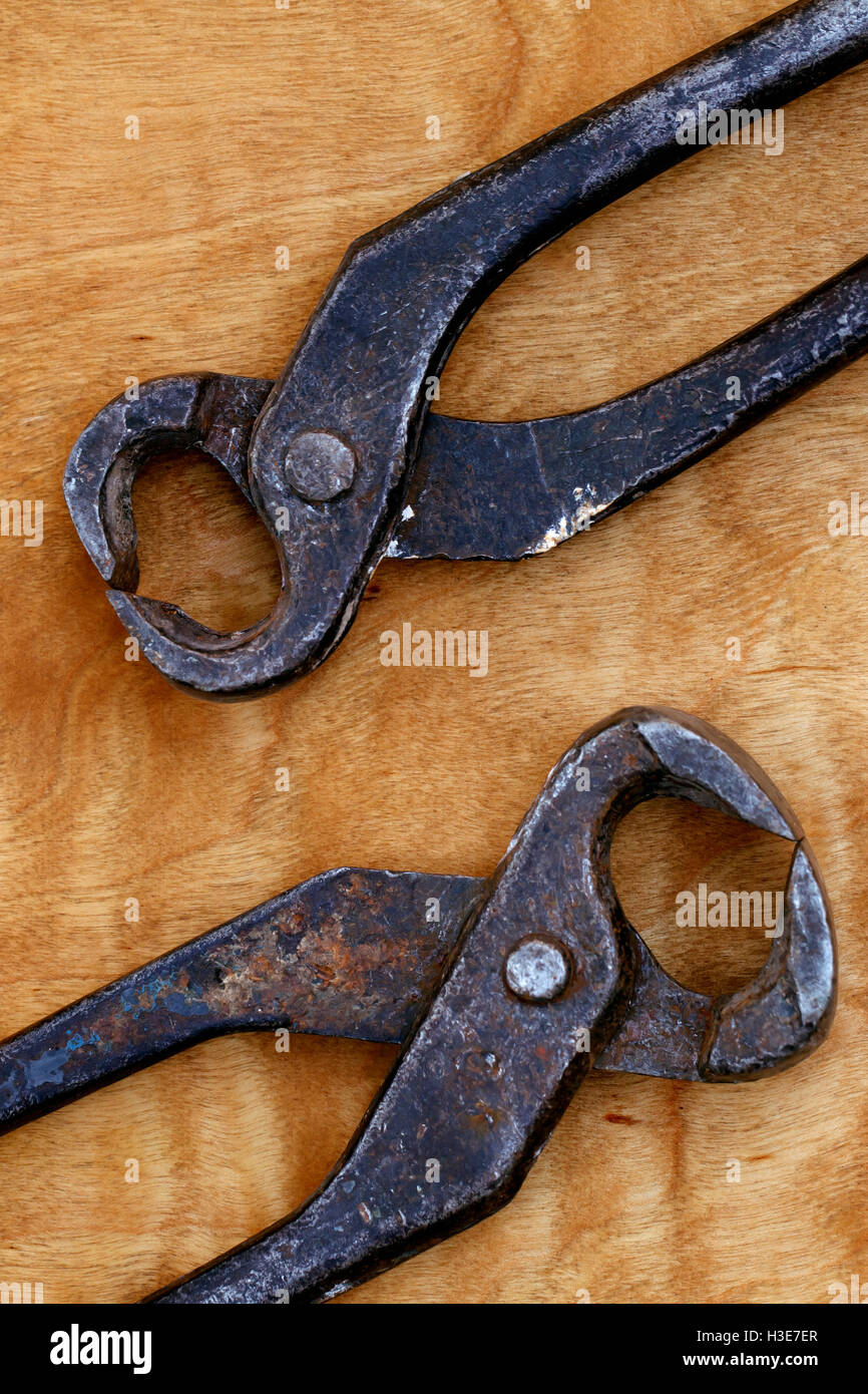 a old vintage tongs tool on a wooden background Stock Photo - Alamy