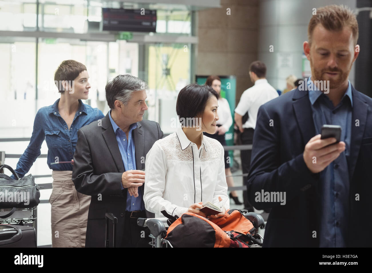 Passengers waiting in queue at a check-in counter with luggage Stock Photo - Alamy