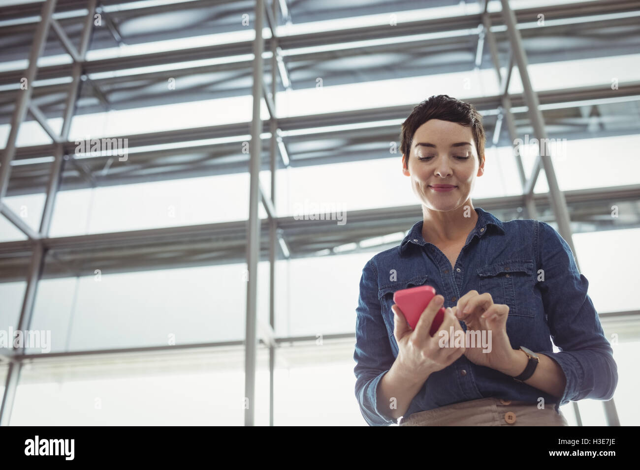 Businesswoman using mobile phone in waiting area Stock Photo - Alamy