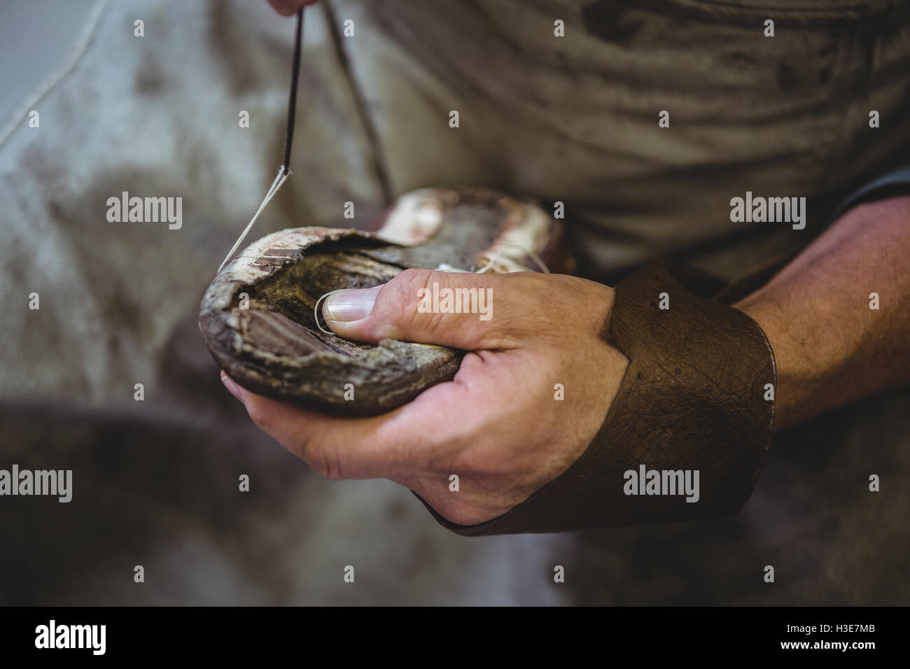 Shoemaker stitching shoe sole with needle Stock Photo - Alamy