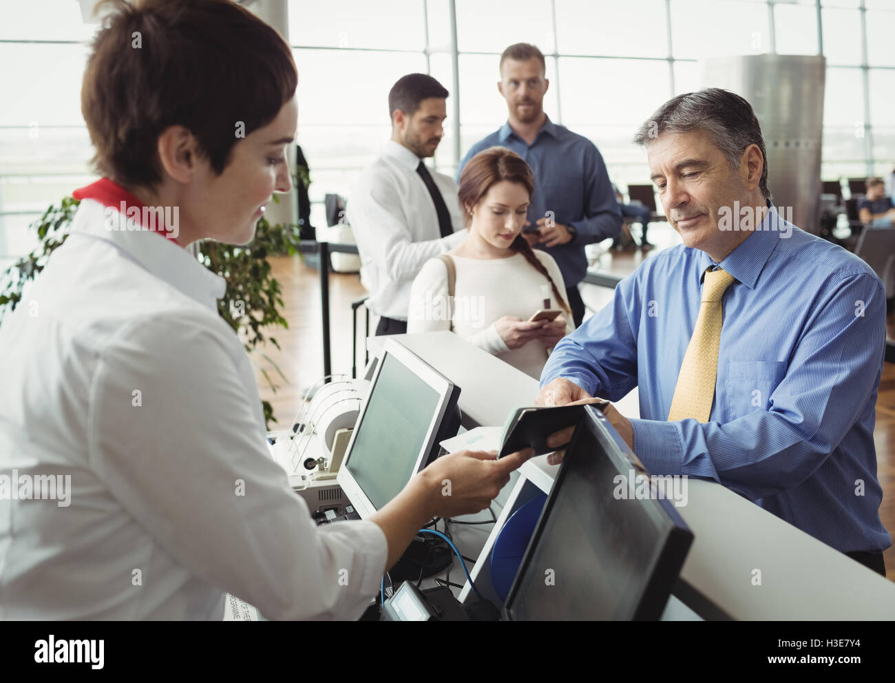 Airline check-in attendant handing boarding pass to passenger Stock ...