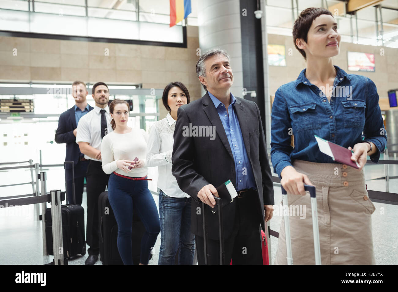 Passengers waiting in queue at a check-in counter with luggage Stock ...