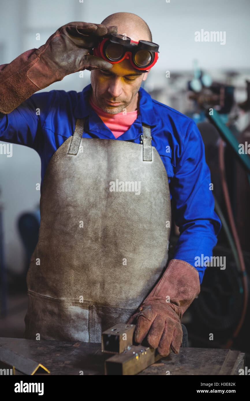 Male welder examining a piece of metal Stock Photo - Alamy