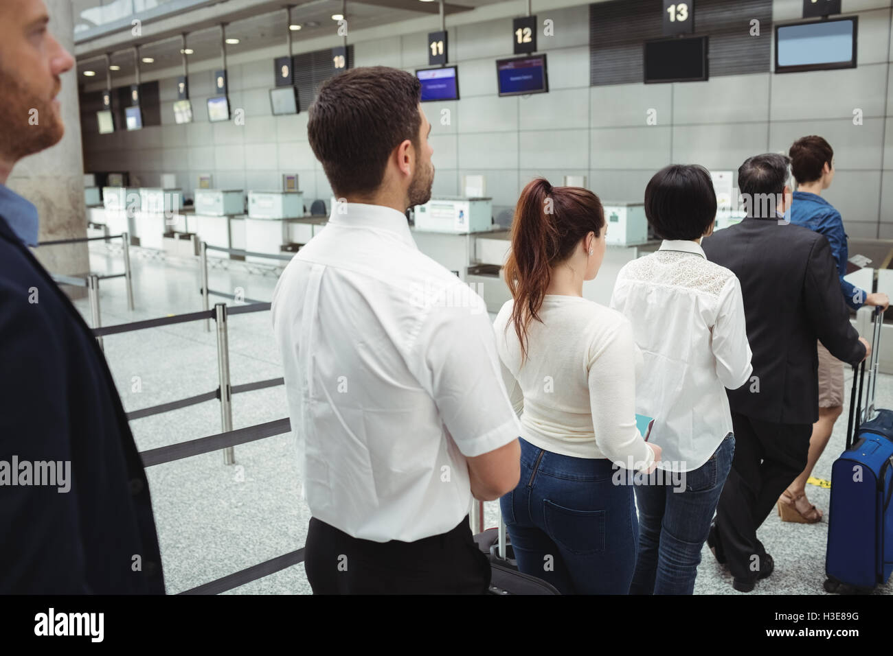 Passengers waiting in queue at a check-in counter with luggage Stock ...