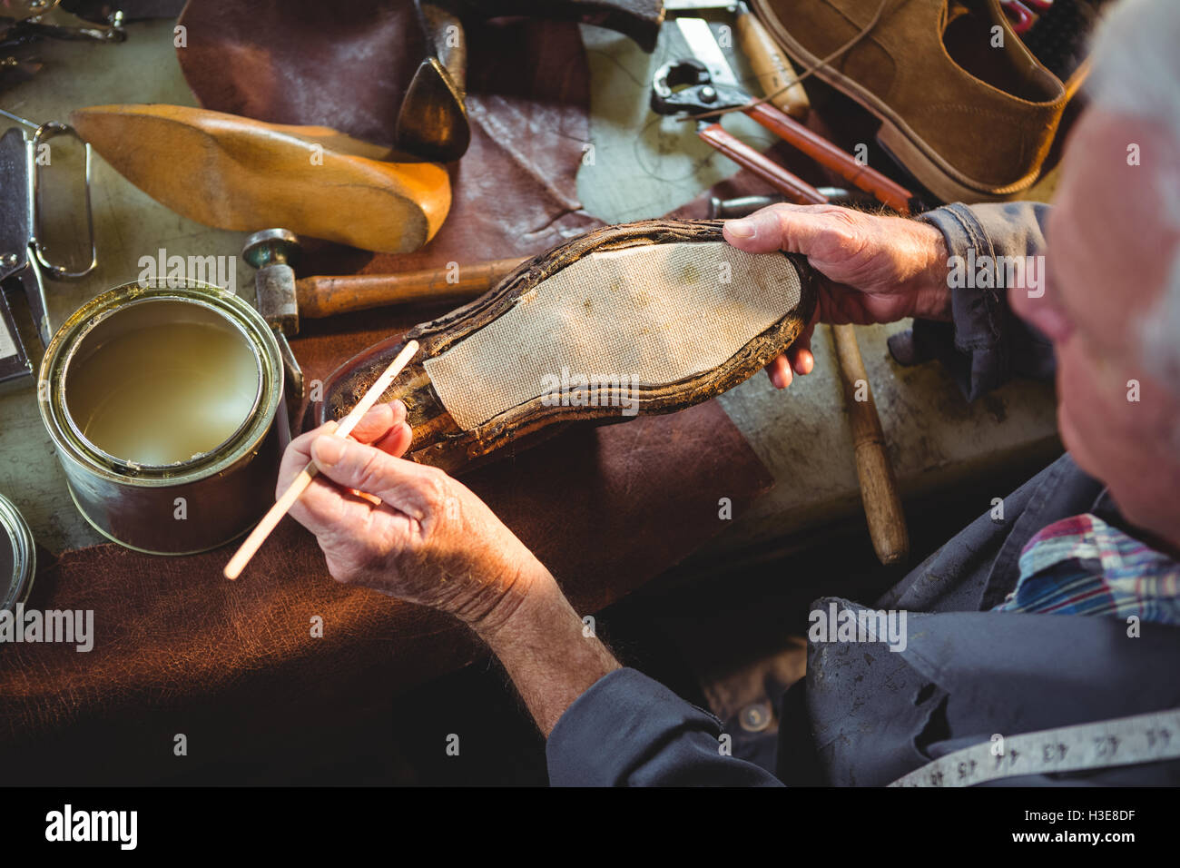 Shoemaker applying glue on shoe sole Stock Photo - Alamy