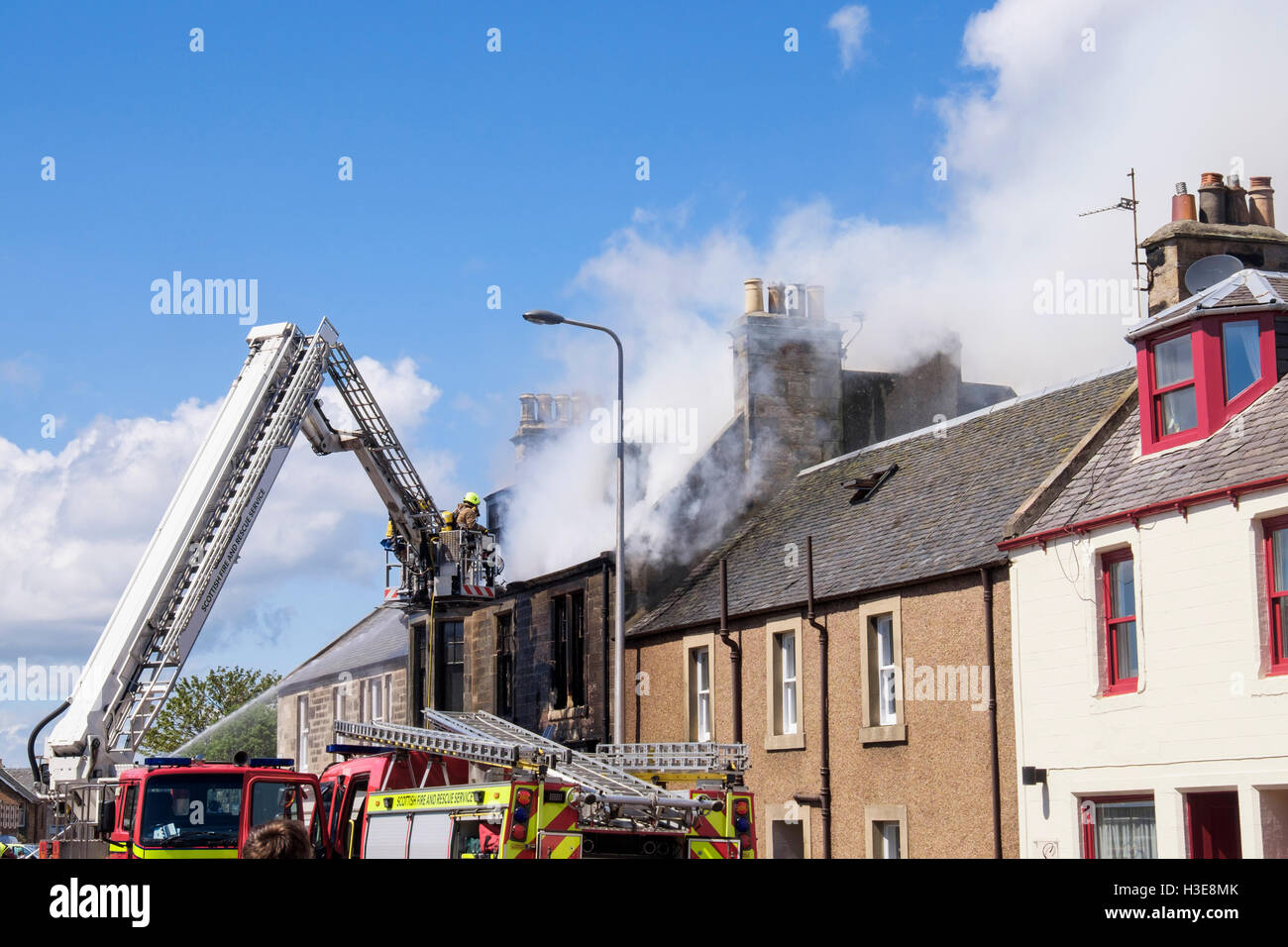Scottish Fire and Rescue Service firefighters up a ladder tackling a ...