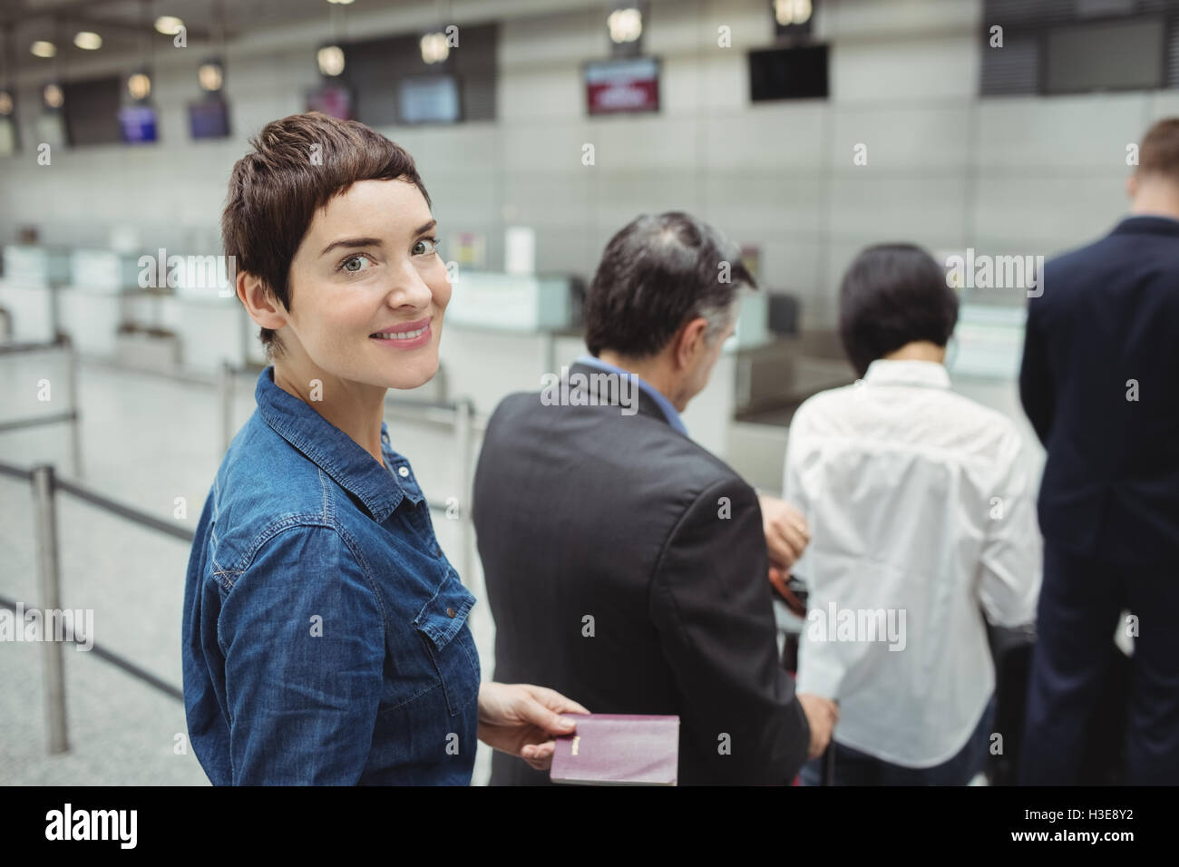Passengers waiting in queue at a check-in counter with luggage Stock Photo - Alamy